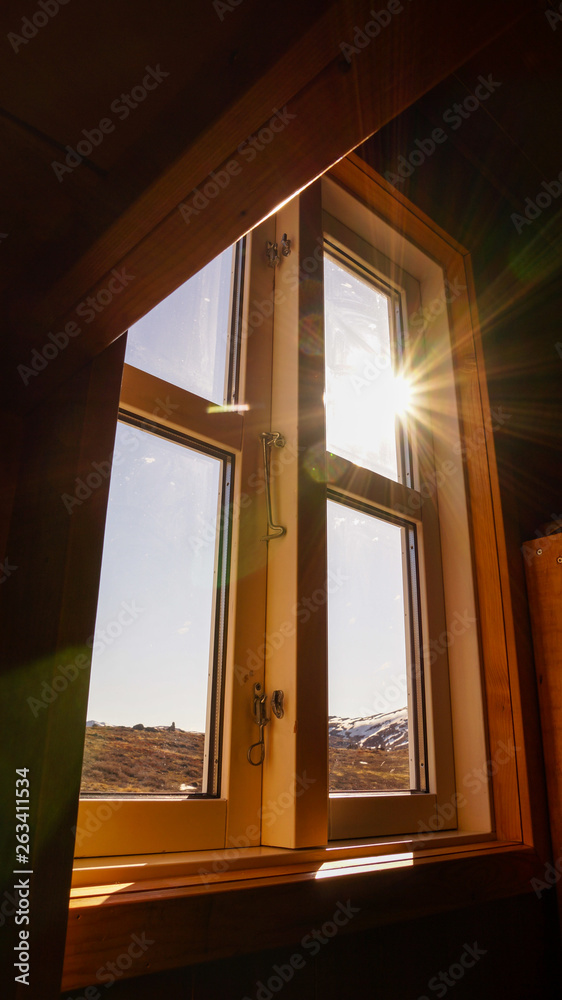 Sun rays shining into a window of a cabin on the Arctic Circle Trail in ...