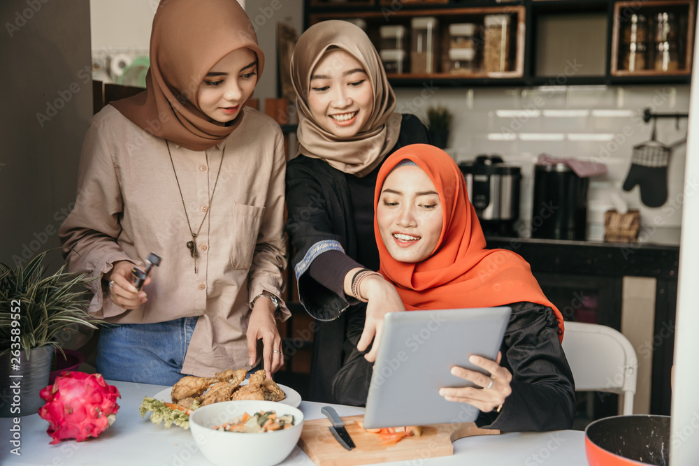 three muslim friend looking tablet and learn to make new food menu in ...