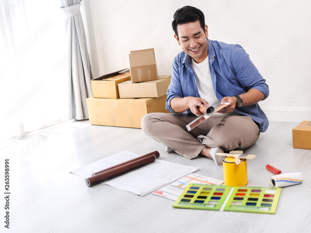 Happy Asian man choosing color palette for his new house. Stock Photo ...