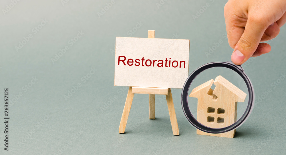 A poster with the inscription Restoration and a broken wooden house ...
