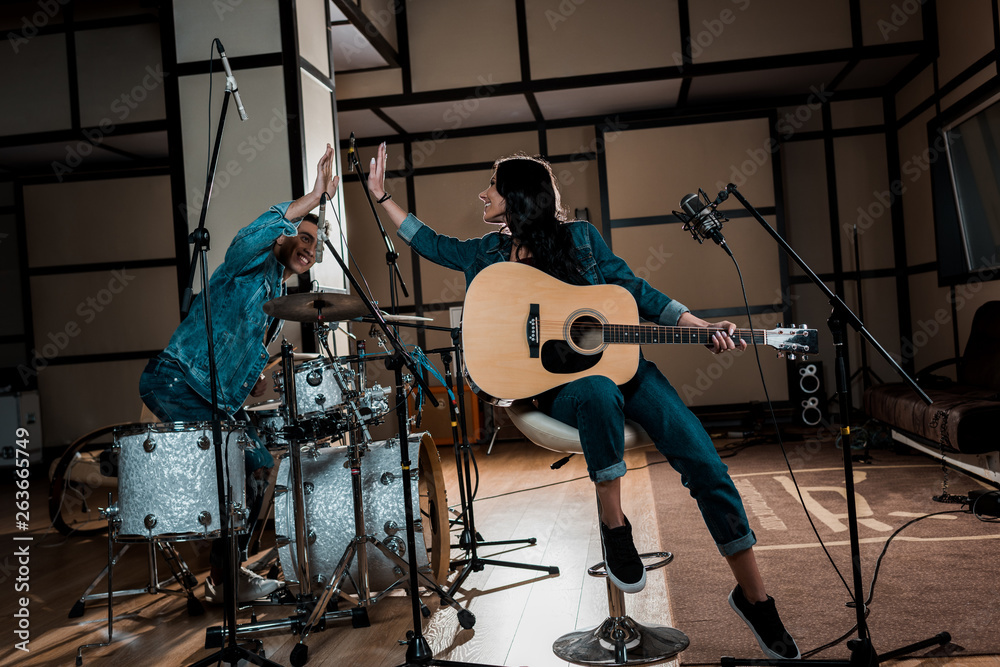 young inspired multicultural musicians giving high five in recording ...