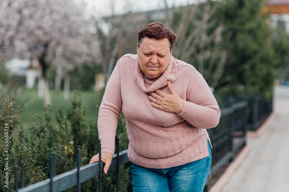 Older and overweight, Middle-age lady touching her chest, suffering ...