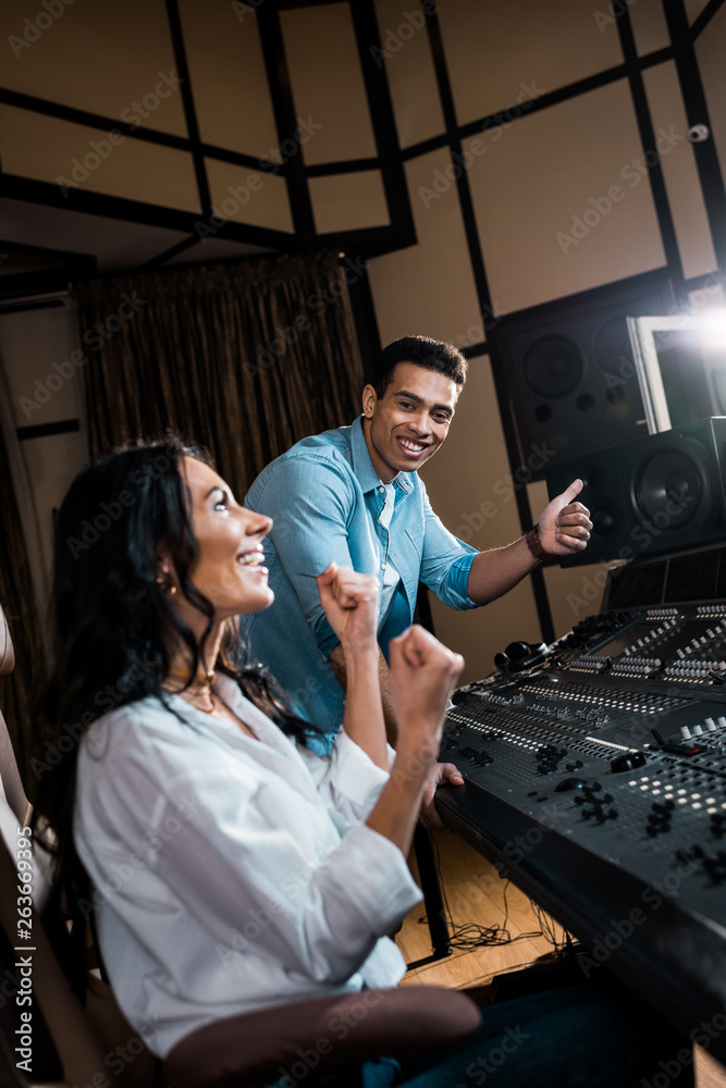 two happy multicultural sound producers showing success gestures in ...