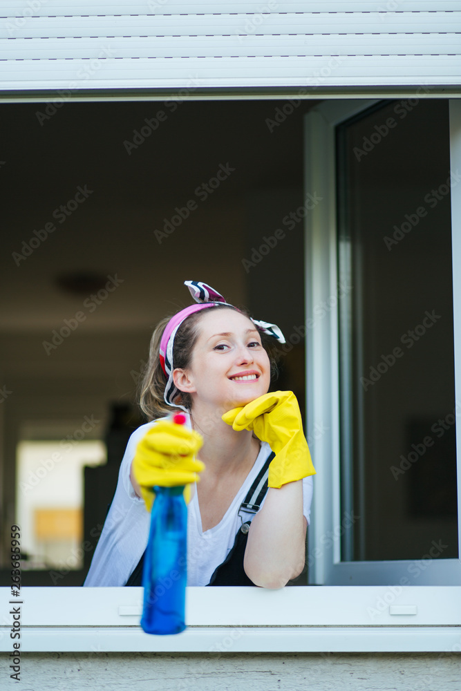 Cleaning. Happy cute girl holding spray bottle for cleaning windows and ...