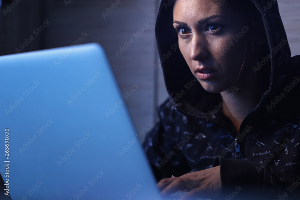 Young female hacker stealing data form laptop. Stock Photo | Adobe Stock