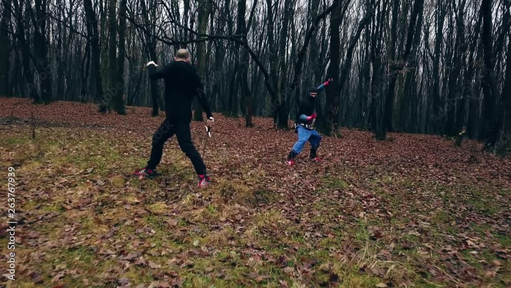 Vidéo Stock Man twirls a sword as another dressed in modern ninja ...