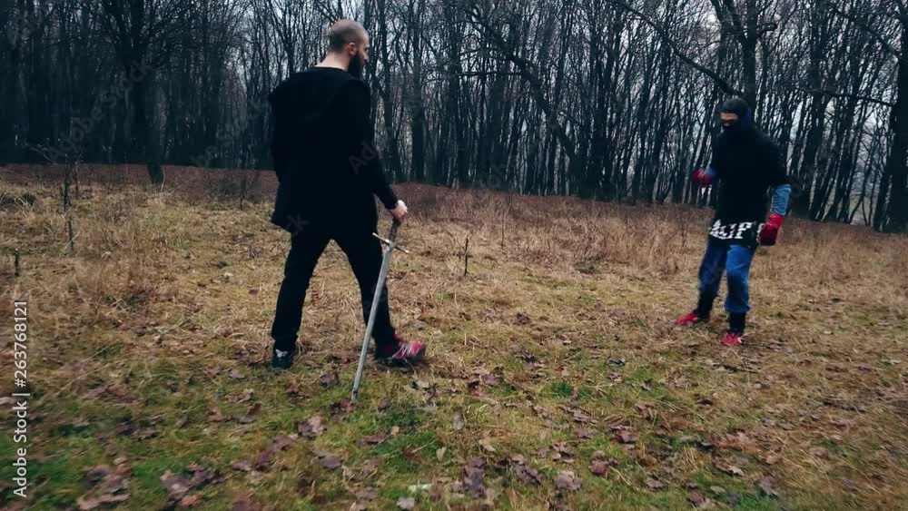 Video Stock Man dressed in black pulls a long silver sword from the ...