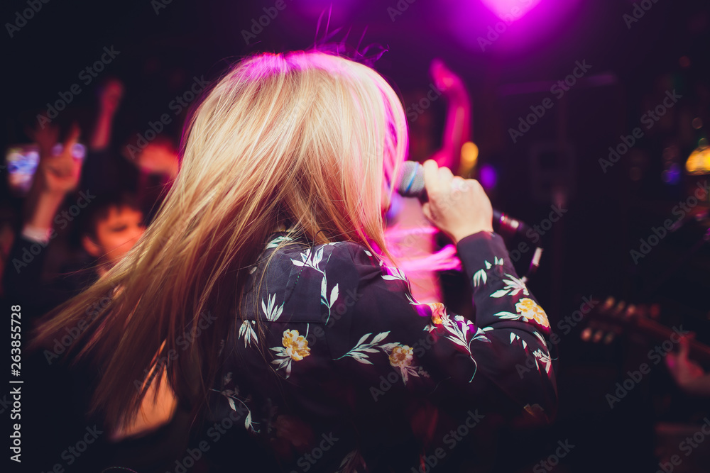 Beauty model girl singer with a microphone singing and dancing over ...