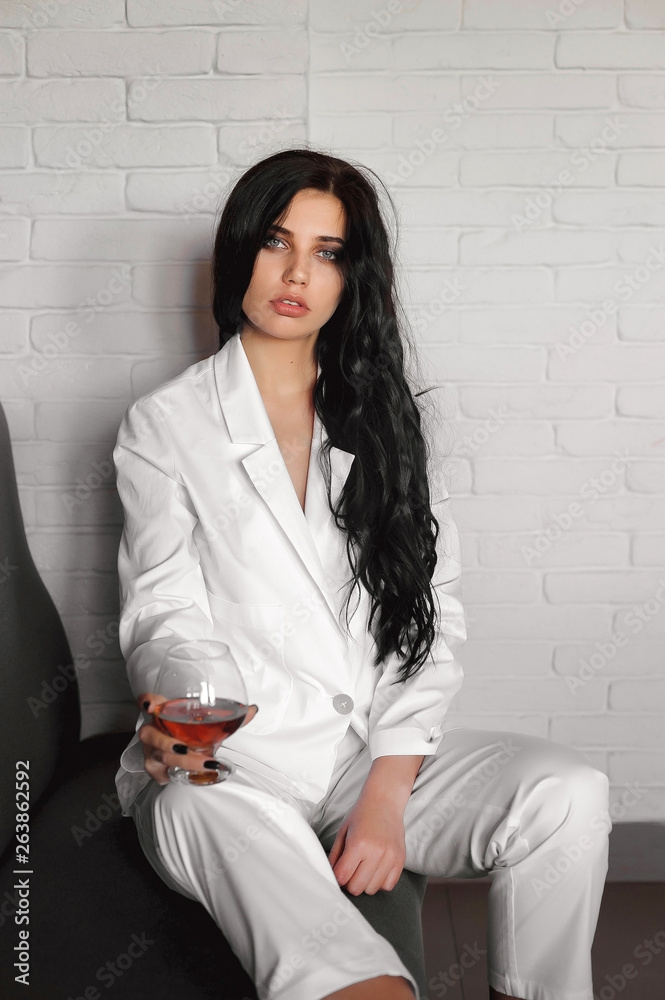 business girl with black hair in a white suit; in a suit without a bra ...