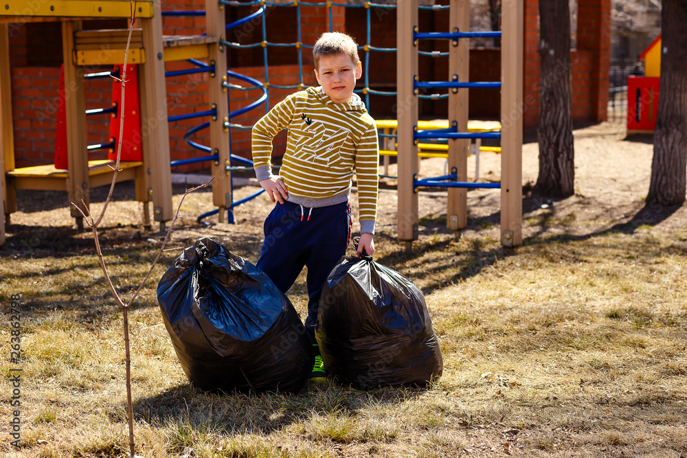 seven-year-old child removes garbage on the Playground in the spring ...