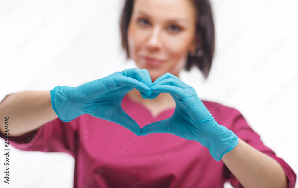 врач держит руки в перчатках в форме сердца. Европейка женщина врач на ...