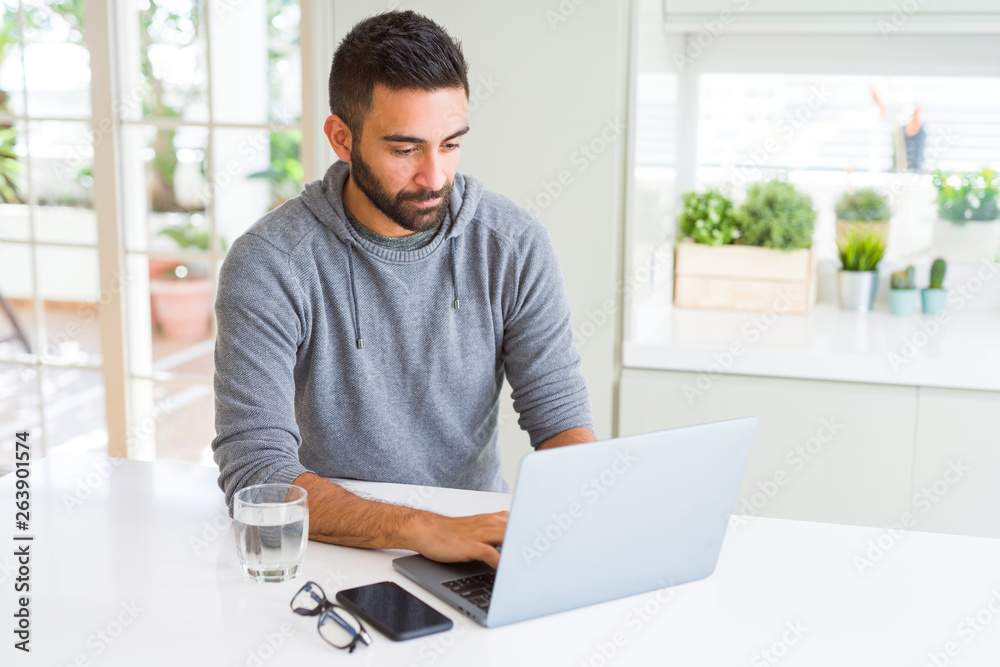 Handsome hispanic man working using computer laptop with a confident ...