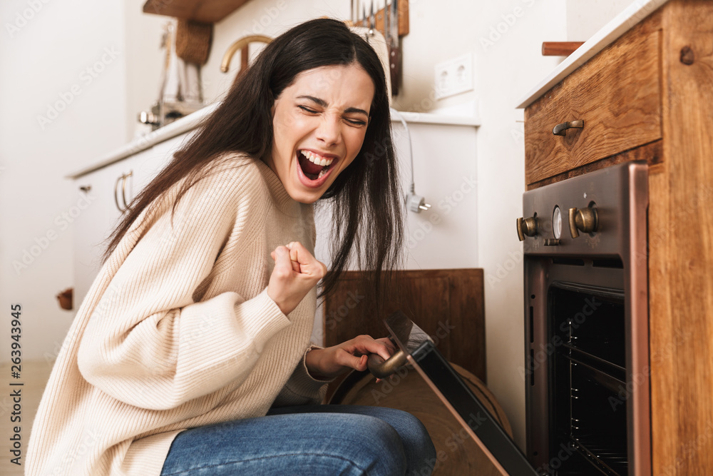 Image of happy brunette woman 30s cooking and waiting for homemade ...