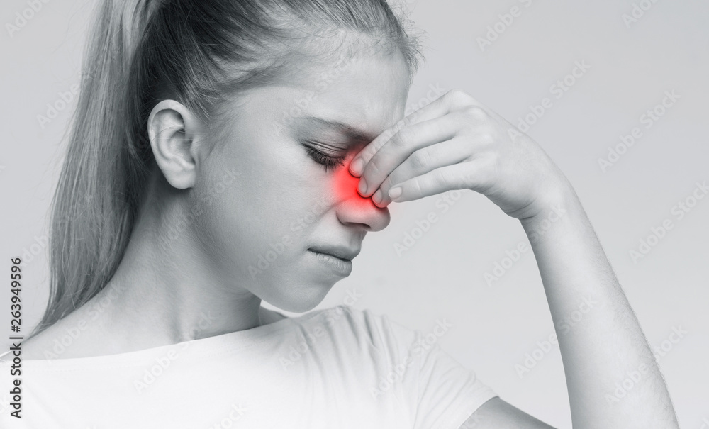 Sad woman holding her nose because sinus pain Stock Photo | Adobe Stock