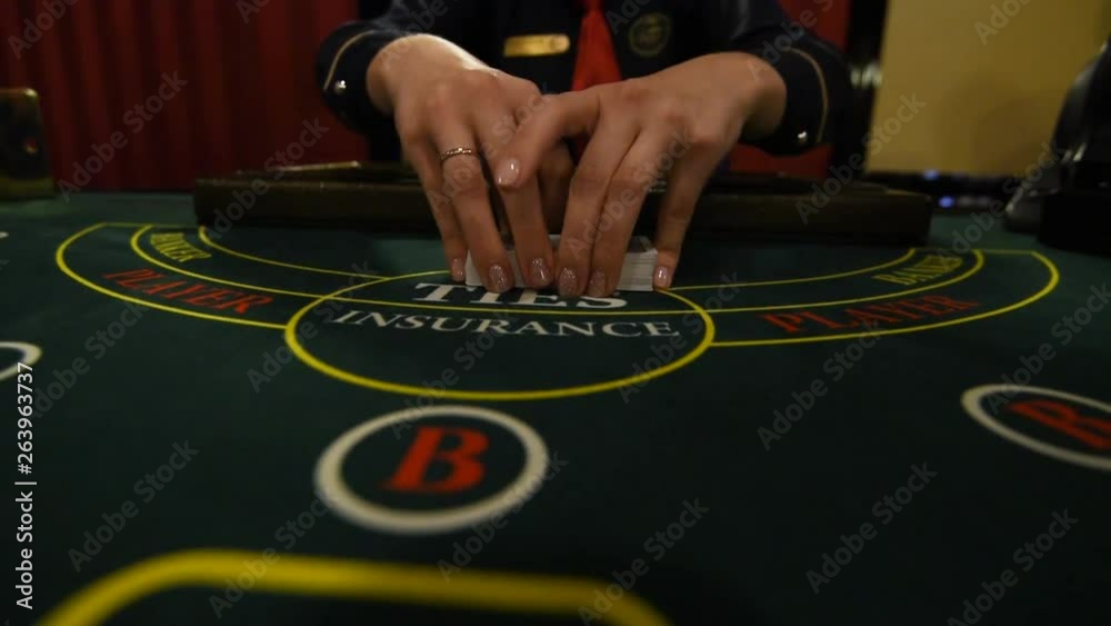 Casino stickman takes the cards from card holder at the game table ...