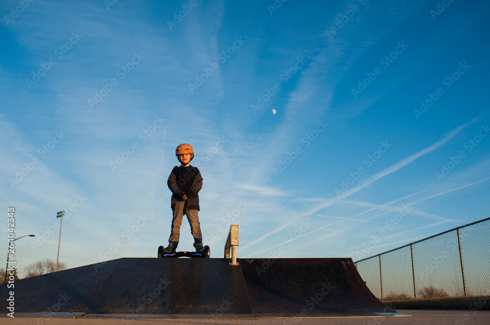 Young boy on top of pyramid ramp on his hover board at skate park Stock ...