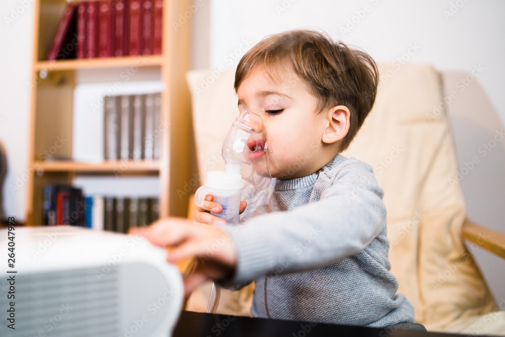 Little boy using steam inhaler nebulizer mask inhalation at home ...
