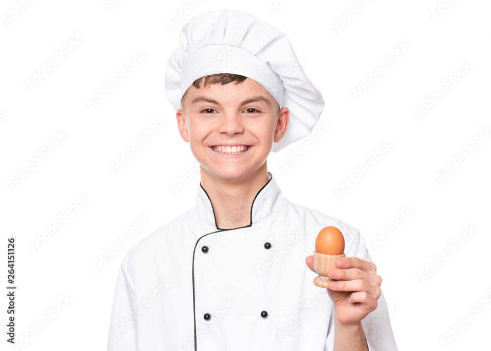 Handsome teen boy wearing chef uniform holding brown egg. Portrait of a ...