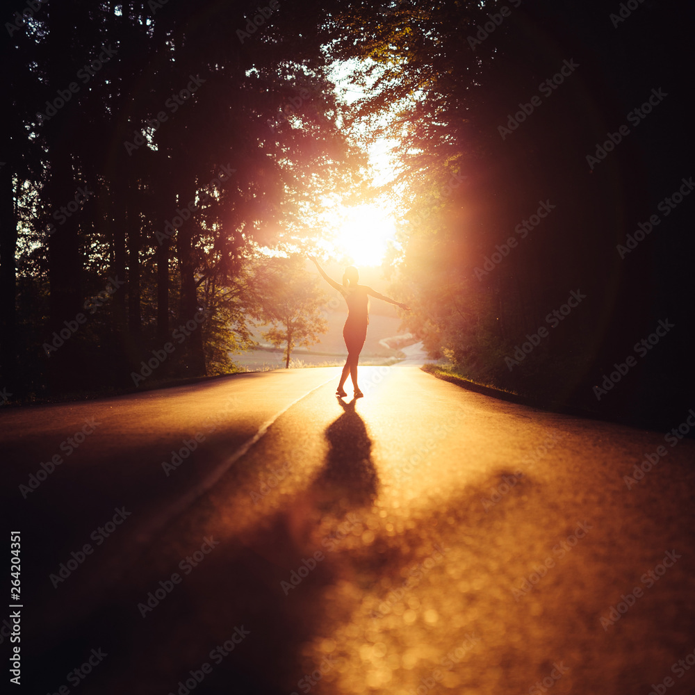 Silhouette of woman captured in relaxed pose with arms outstretched and ...