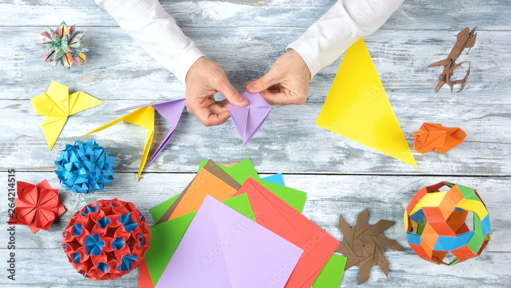 Hands doing origami swallows. Person making plane from colorful paper ...