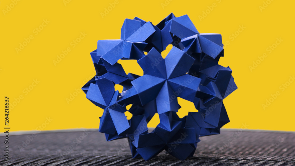 Blue origami floral ball on yellow background. Spherical origami figure ...