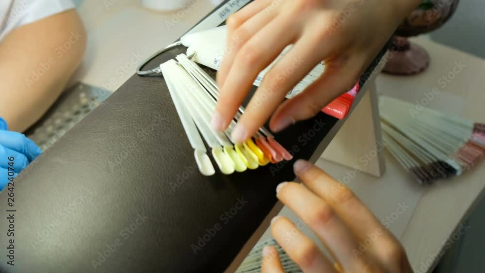 Close up hands and nail polish samples. Girl choosing nail color tester ...