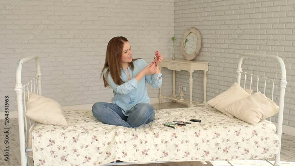 A young diabetic woman sits on a bed at home and dials insulin in a ...