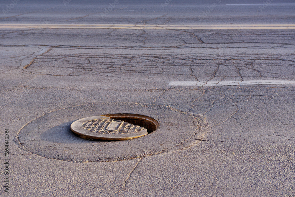 Broken iron manhole cover dangerously open in the middle of the street ...