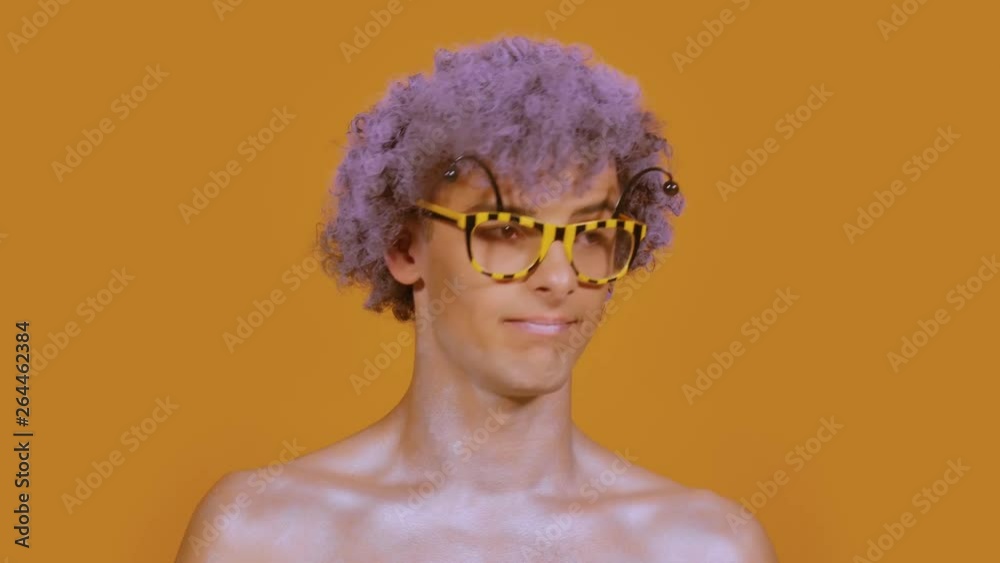 Curly stylish guy in funny glasses waving his head fun on a color ...