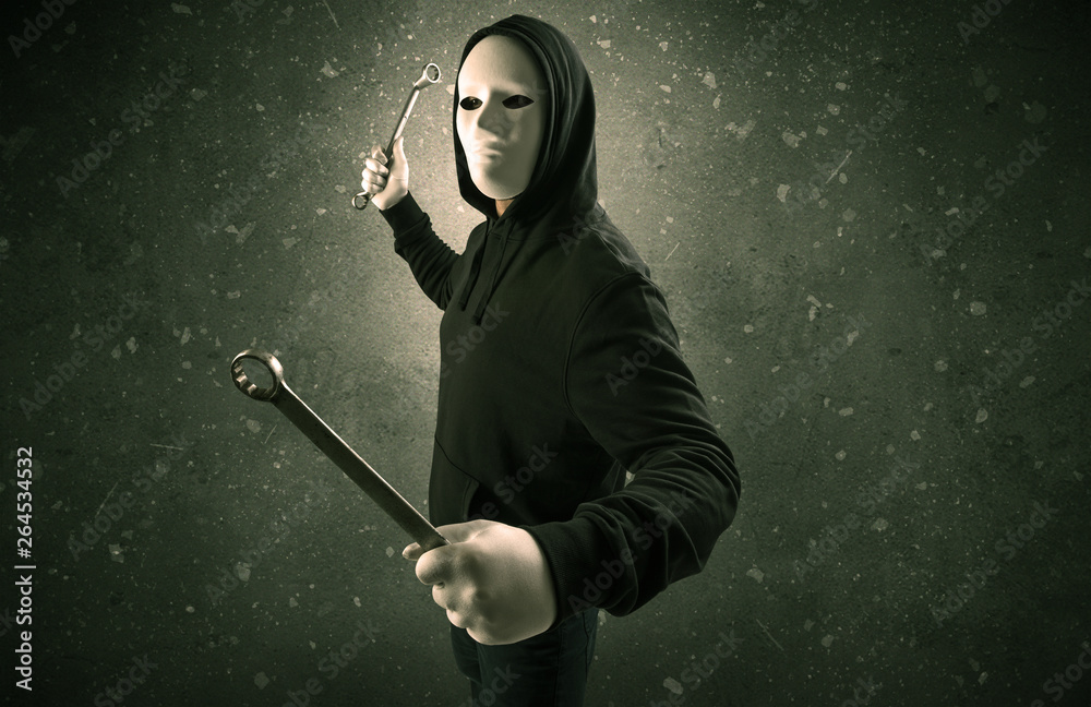 Masked armed villain in empty dark room with gun ax chainsaw mallet ...