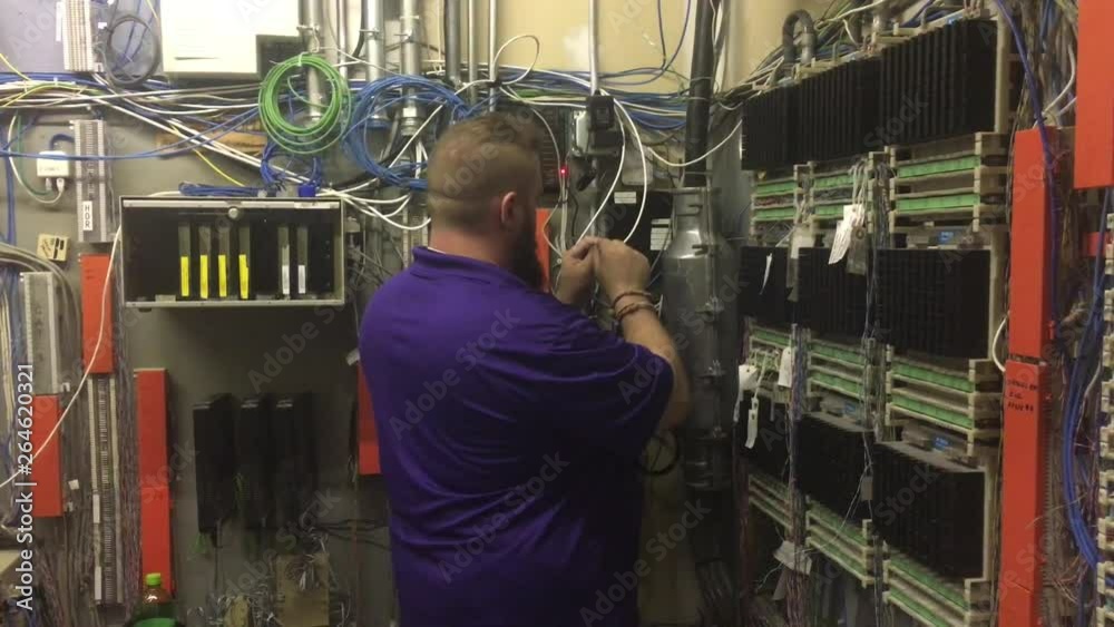 Man working on wires in a high tech room with communication wiring and ...