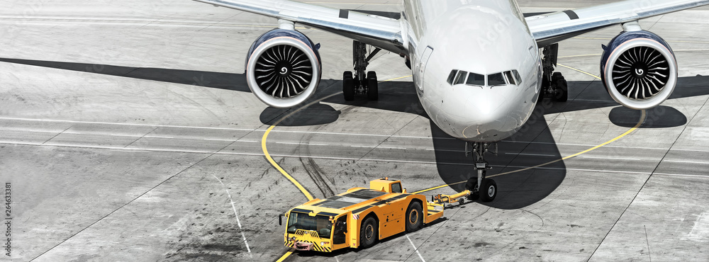 airplane on airport runway with pushback tractor attached to plane nose ...