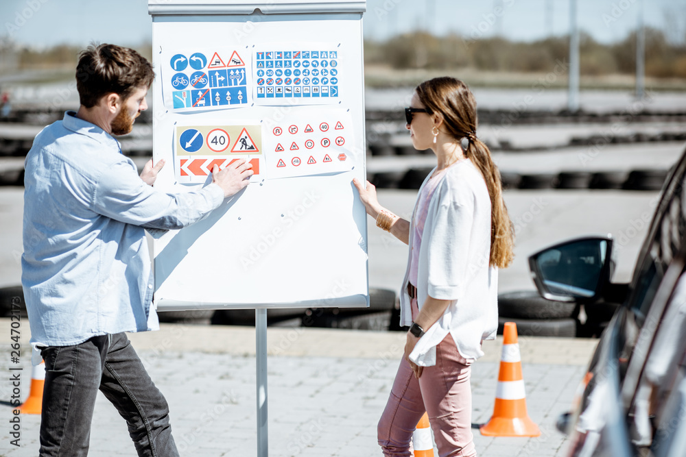 Male instructor showing traffic signs to a young female student ...