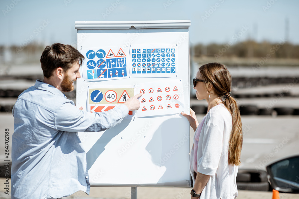 Male instructor showing traffic signs to a young female student ...
