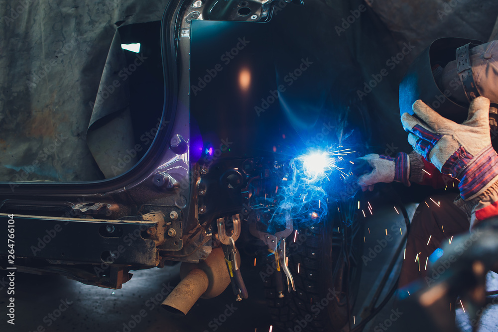 professional repairman worker in automotive industry welding metal body ...