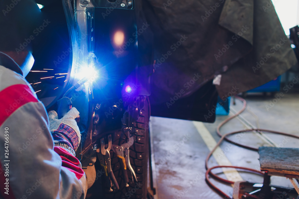 professional repairman worker in automotive industry welding metal body ...