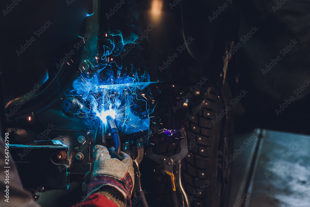 professional repairman worker in automotive industry welding metal body ...