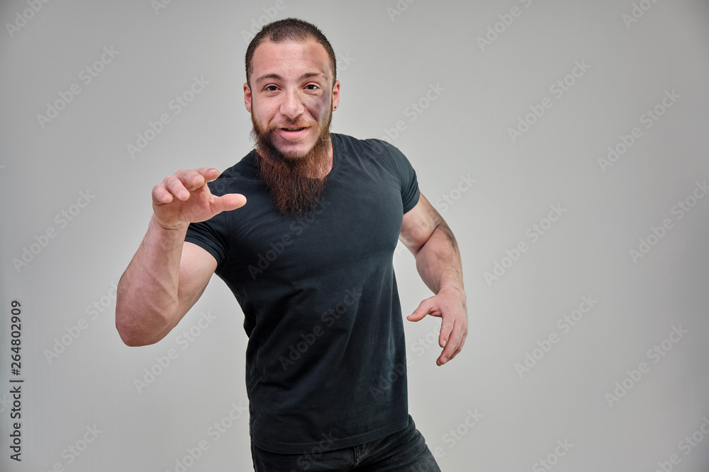 Young brutal man with a beard, bodybuilder in a black t-shirt is ...
