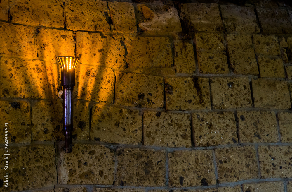 lighted medieval castle torch hanging on a stone wall, vintage objects ...