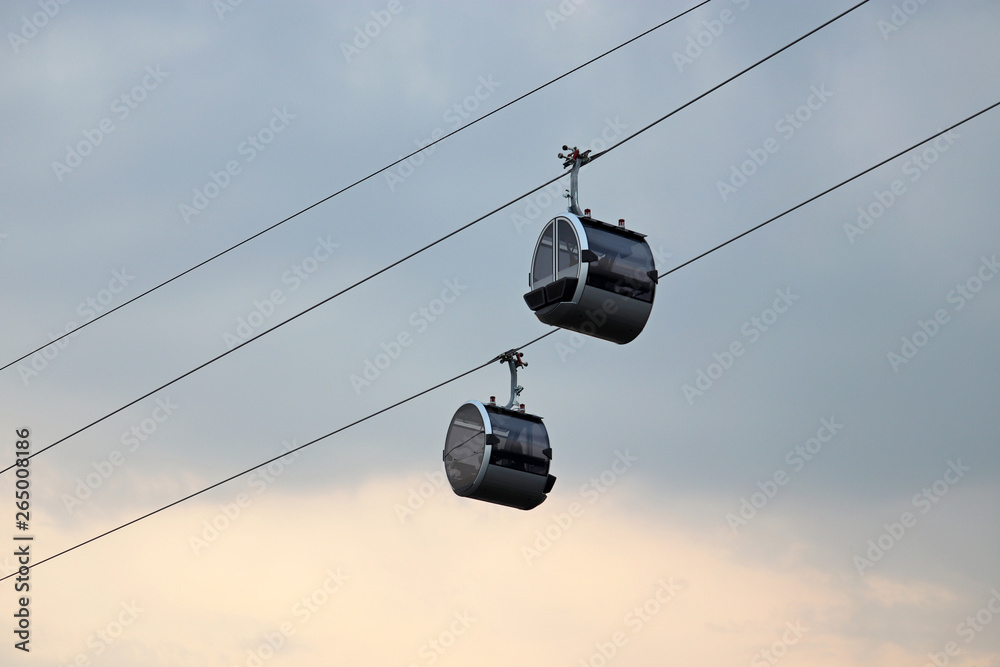 Cable car cabins on background of cloudy evening sky. Ropeway gondola ...
