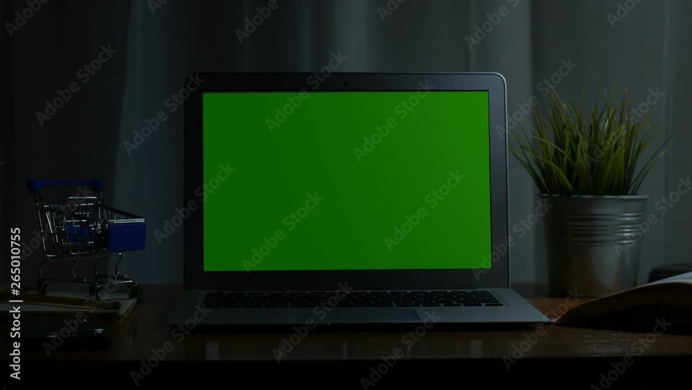Laptop with green screen. Dark office. Dolly in. Perfect to put your ...