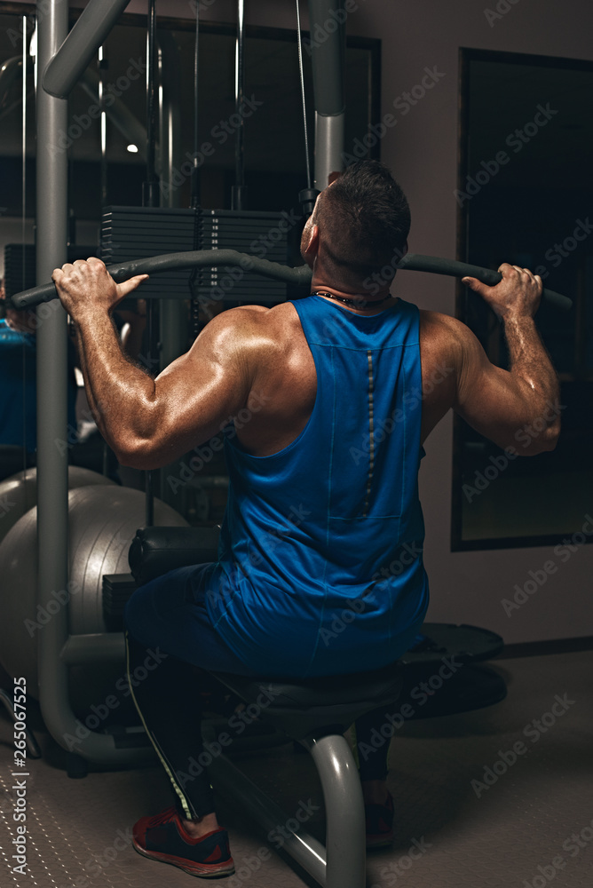 Strong male bodybuilder doing exercise for back with lat pulldown ...
