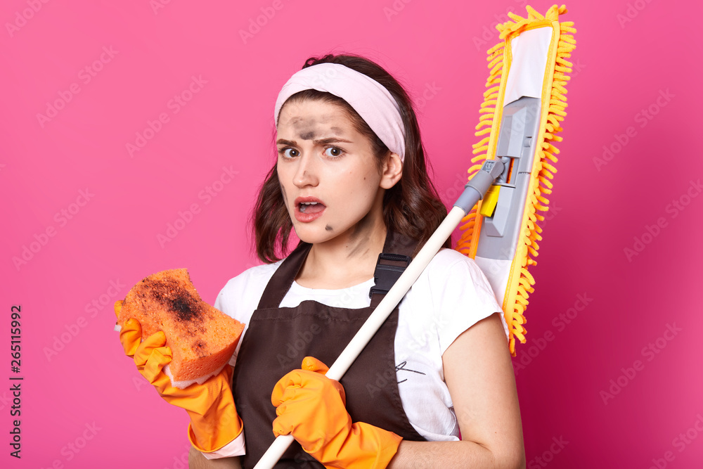 Energetic surprised slender model holds broom on her shoulder, ready to ...