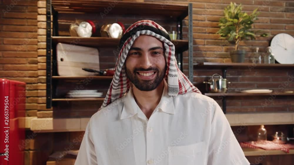Smiling young man wearing traditional emirates clothes look at camera ...