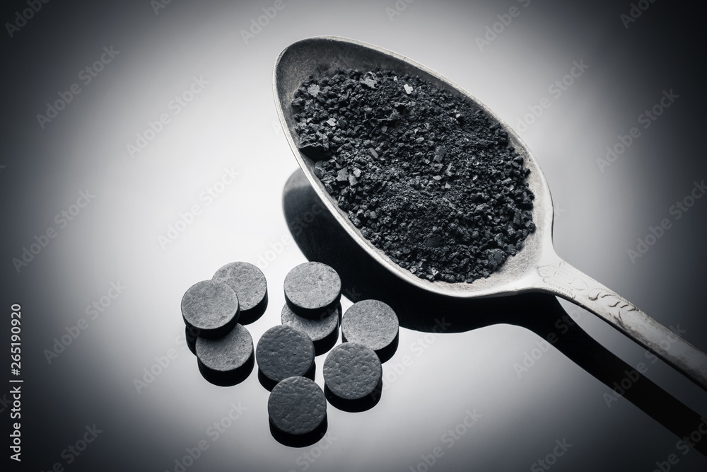 Activated carbon in a spoon and on a reflective surface top view Stock ...
