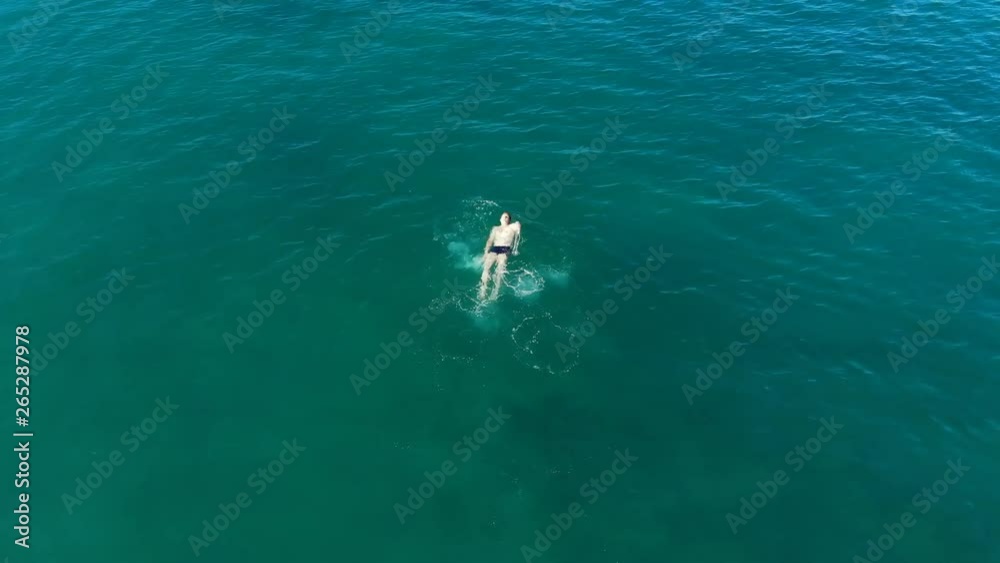 Man leisurely swim on back at sea, aerial shot. Freestyle or backstroke ...