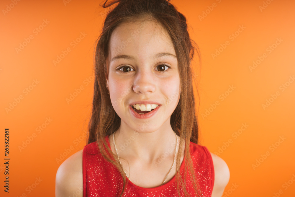 The little girl in a red dress. It is isolated on a orange background ...