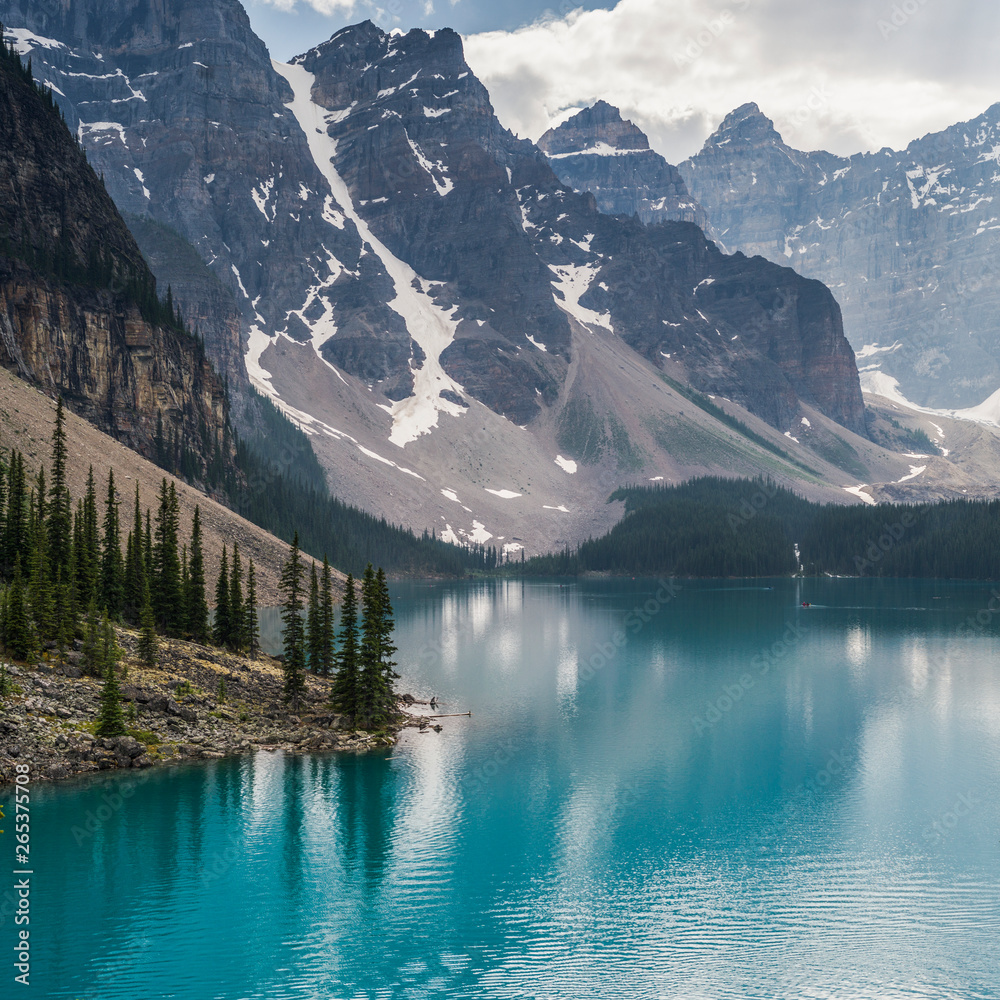 The stunning blue water of Moraine Lake with snow on the rugged ...