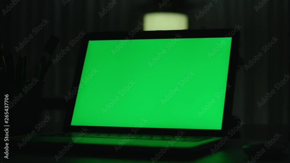 Laptop with green screen. Dark office. Perfect to put your own image or ...