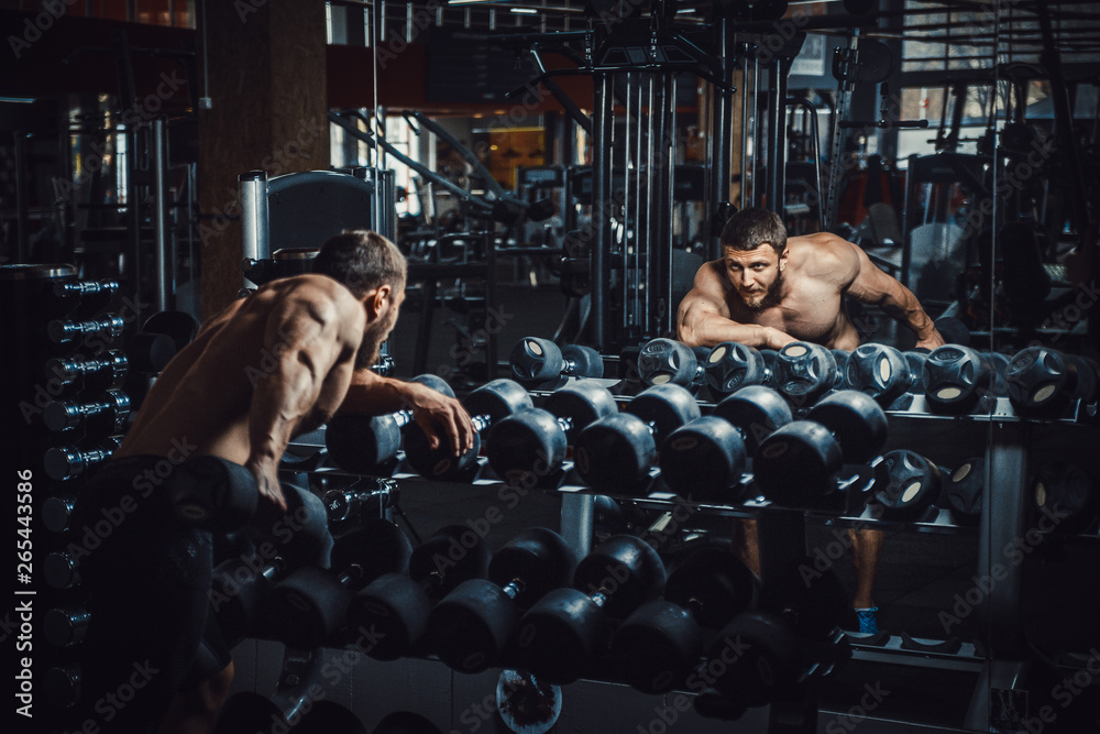 Good looking young man bodybuilder doing triceps kickback lifting ...